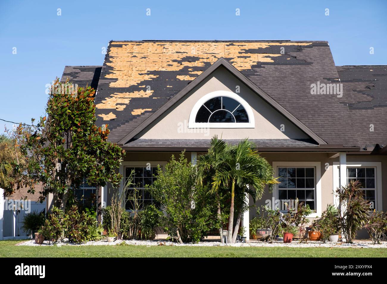 Wind damaged house roof with missing asphalt shingles after hurricane ...