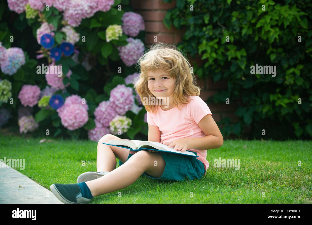 Kid boy reading interest book in the garden. Summertime fun. Cute boy ...