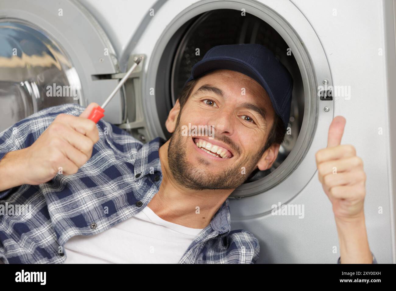 serviceman by washing machine holding screwdriver with thumbs up Stock ...