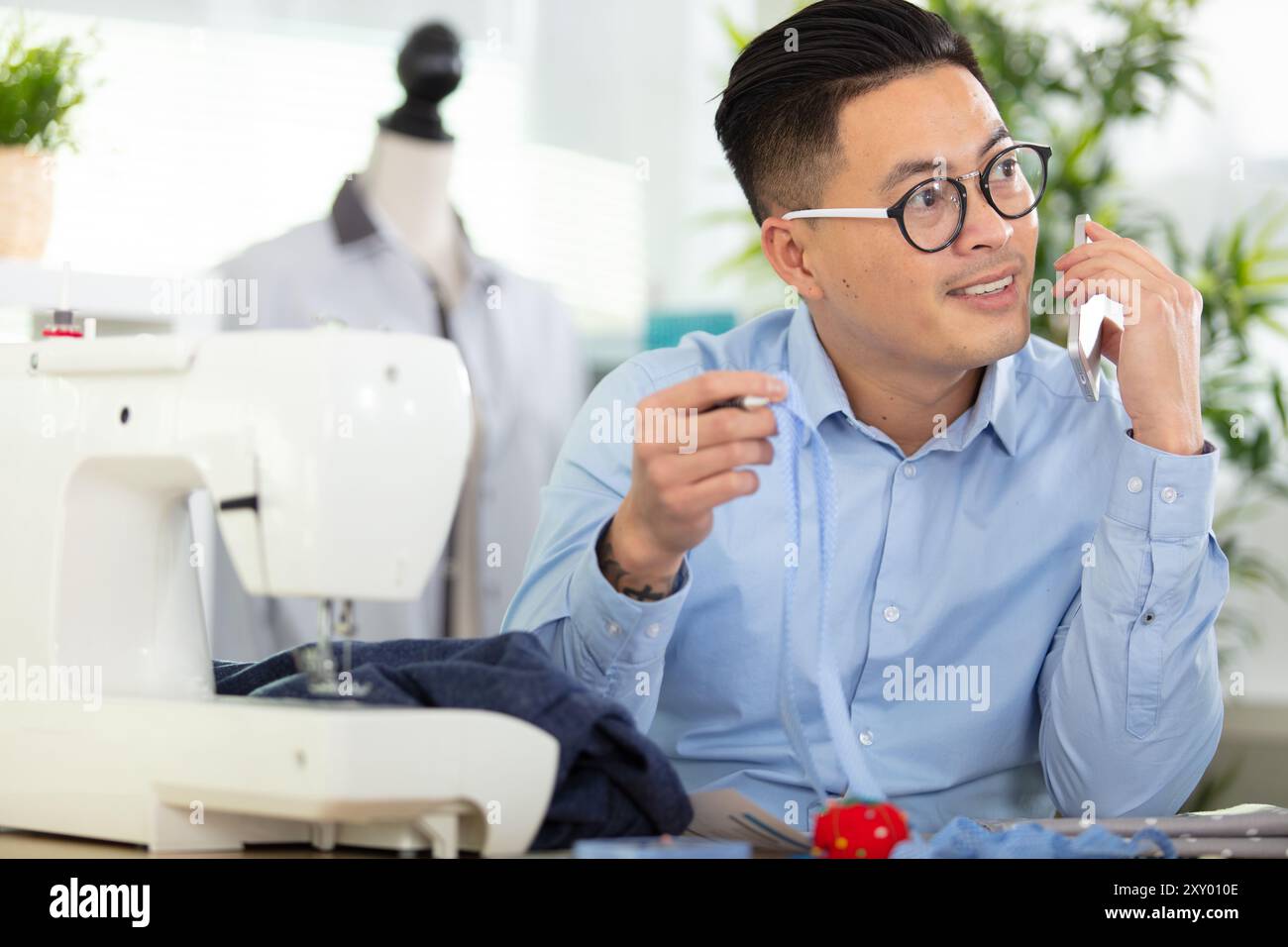handsome fashion designer sewing with a sewing machine Stock Photo - Alamy