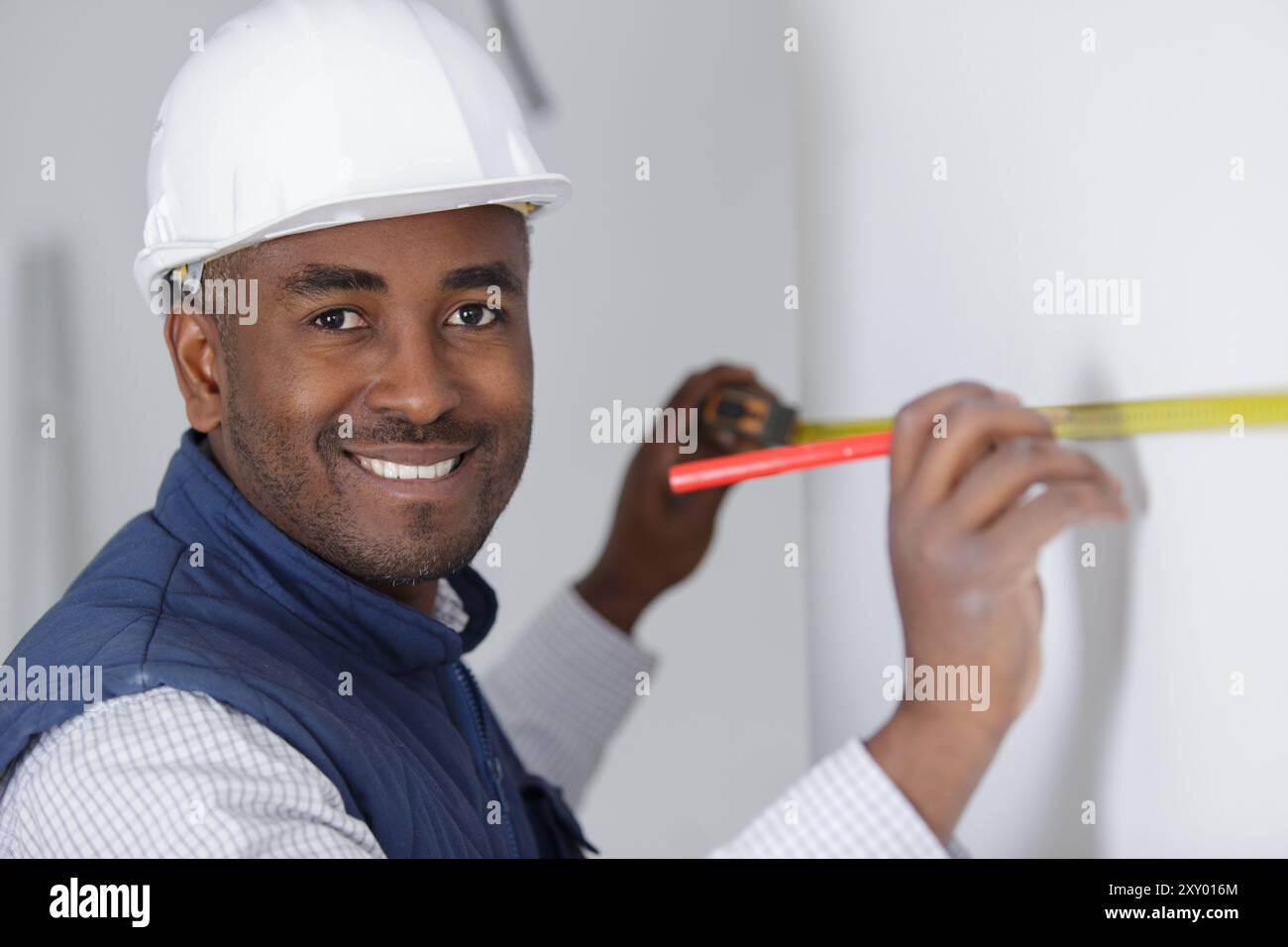 builder measures the distance on a white wall Stock Photo - Alamy