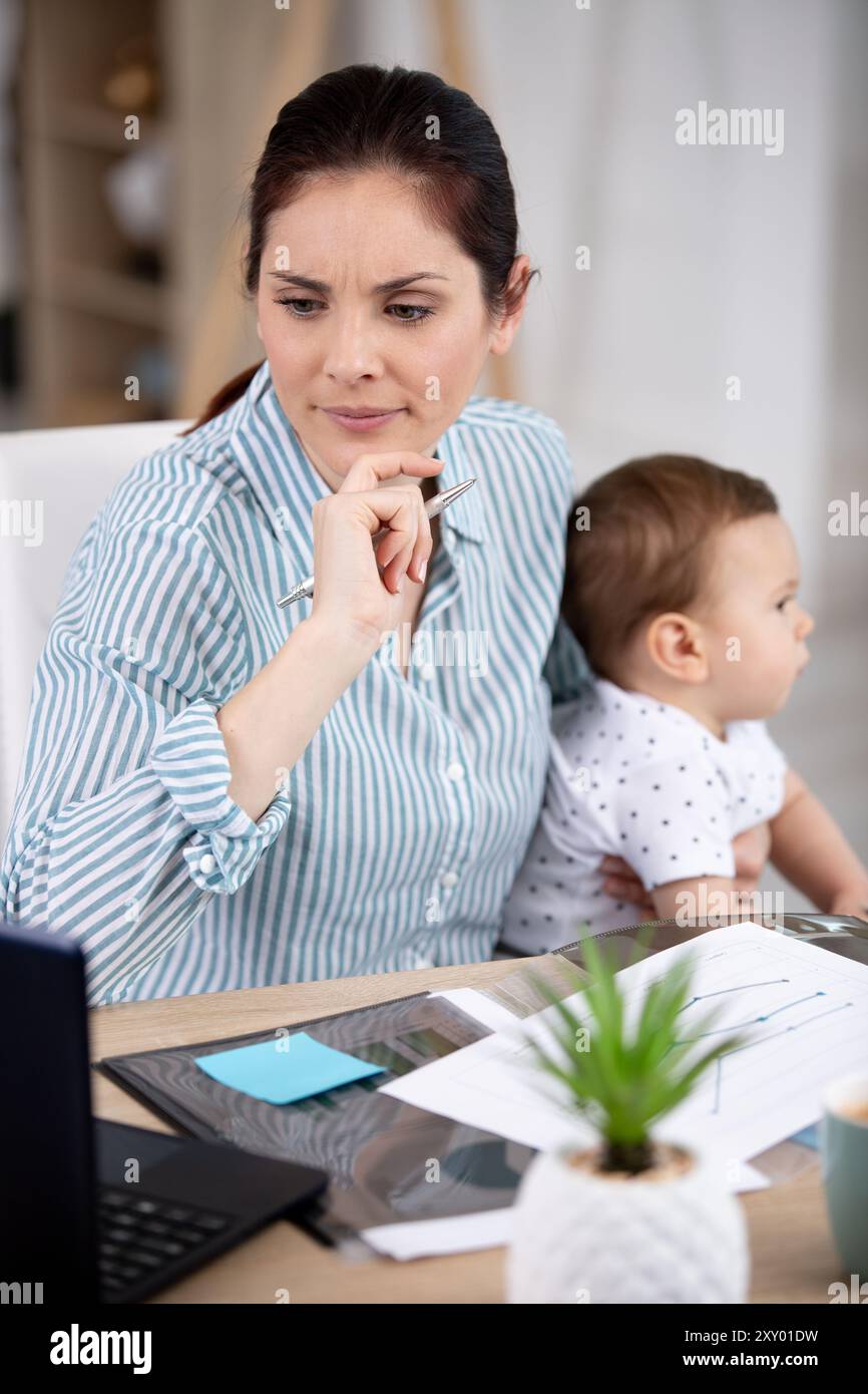 multitasking business woman sitting with her baby at the office Stock ...