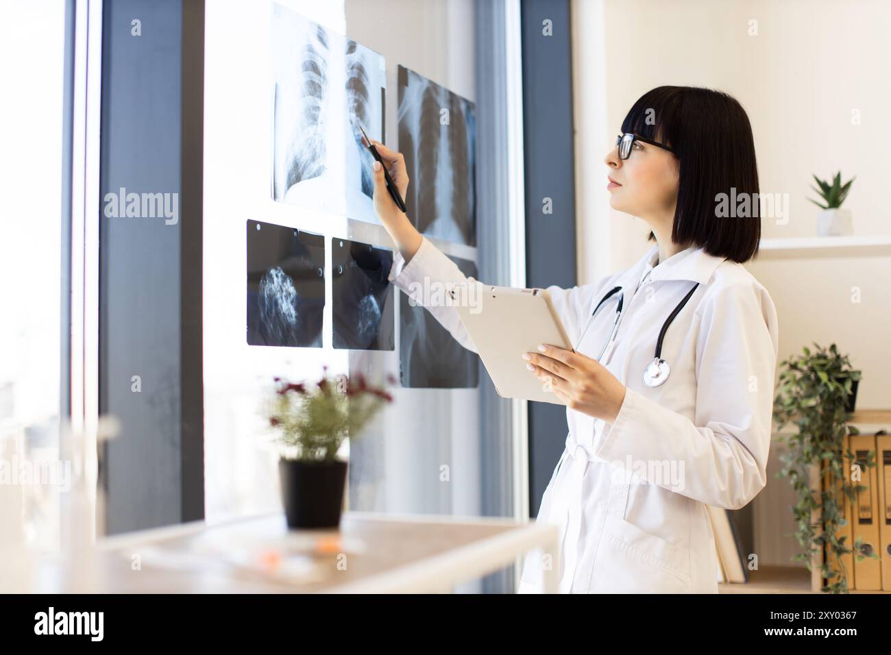 Female doctor analyzing X-rays in bright modern office Stock Photo - Alamy