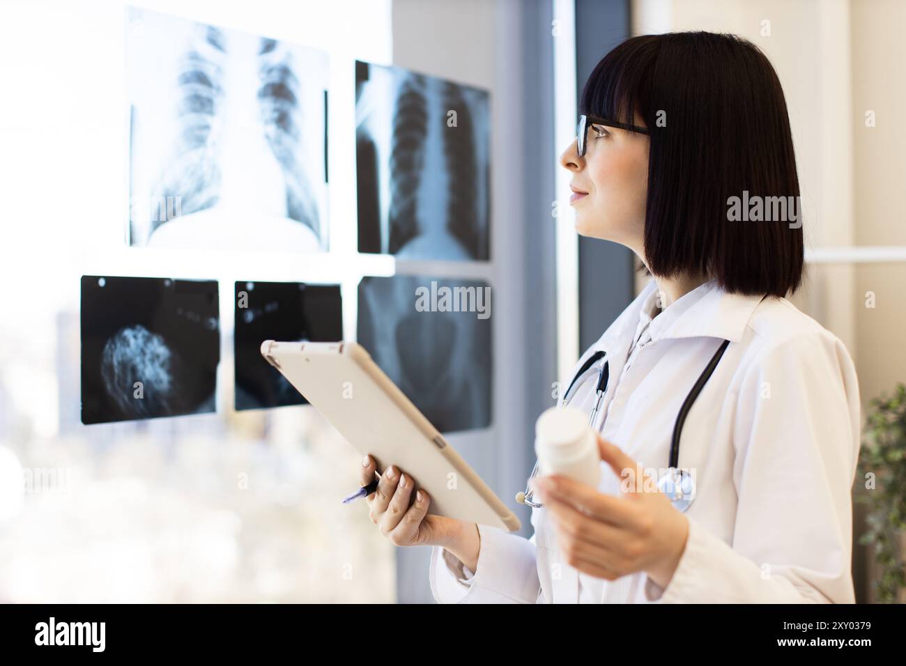 Female doctor examining x-rays with tablet and medication Stock Photo ...