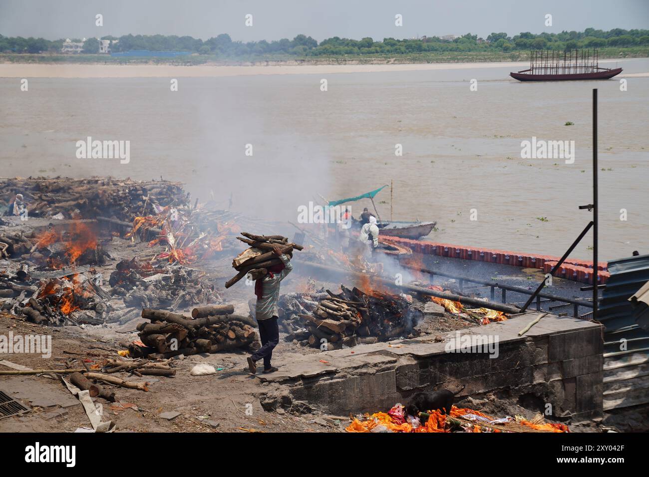 Varanasi, India. 19th July, 2024. A man brings more wood to pyres where ...