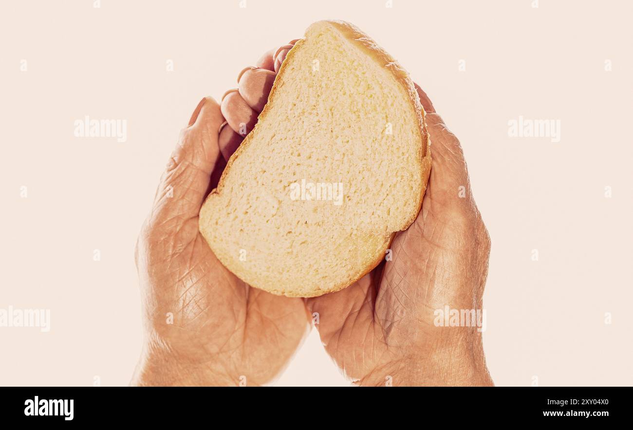 Slice of bread in old wrinkled hands against white background, close-up ...