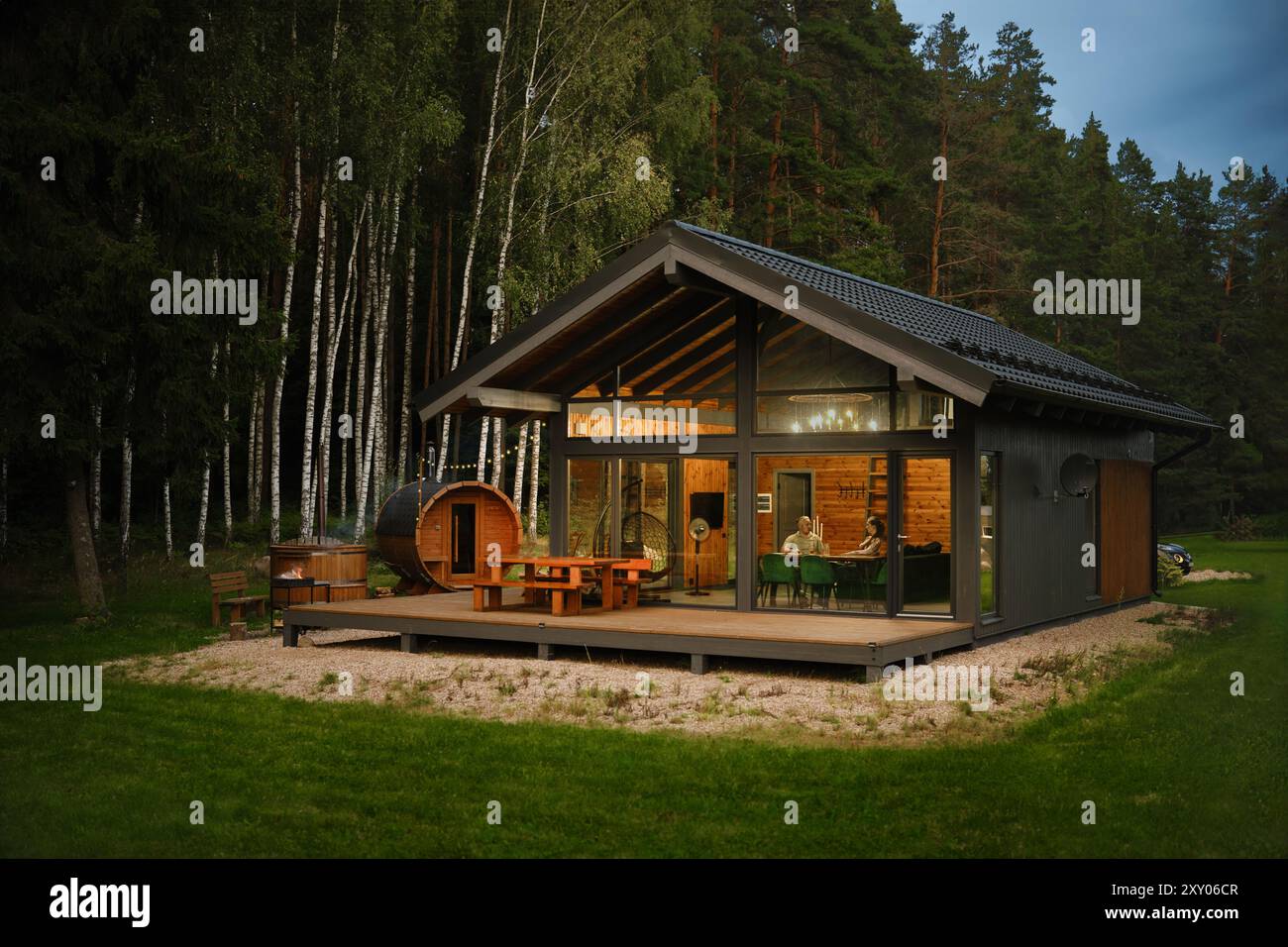 A modern cabin with a large glass windows and wooden deck with patio ...