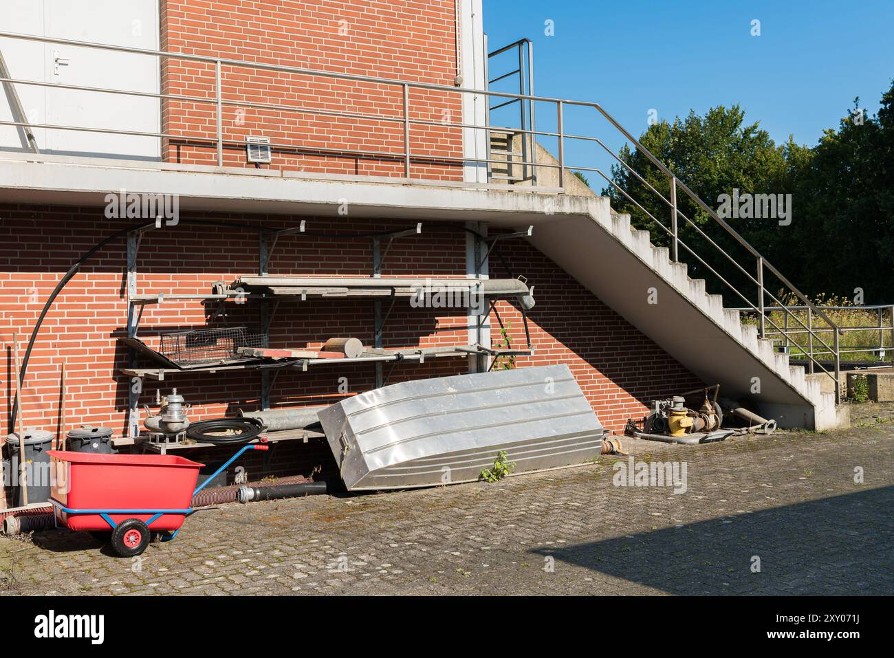 Various tools and a metal boat stacked under the concrete stairs of a ...
