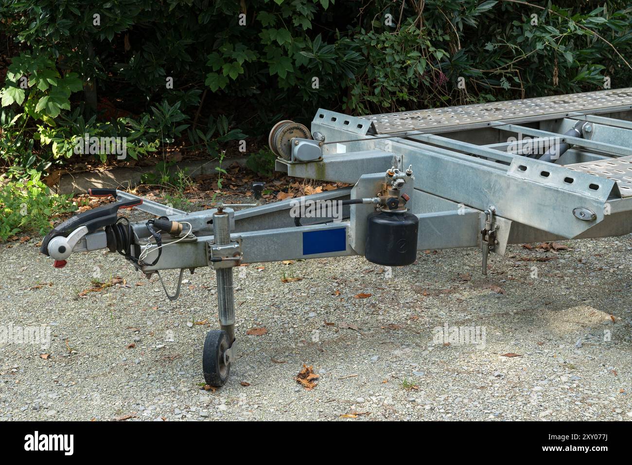 A close-up shot of a metal trailer hitch and chassis parked on a gravel ...