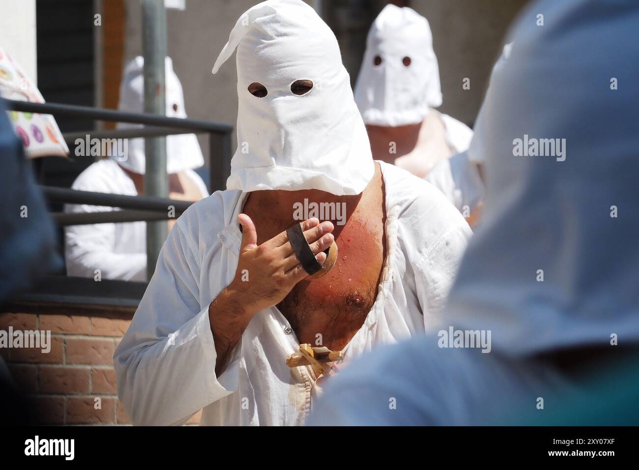 Hooded men dressed in white "Battenti" repeatedly beat their chests ...