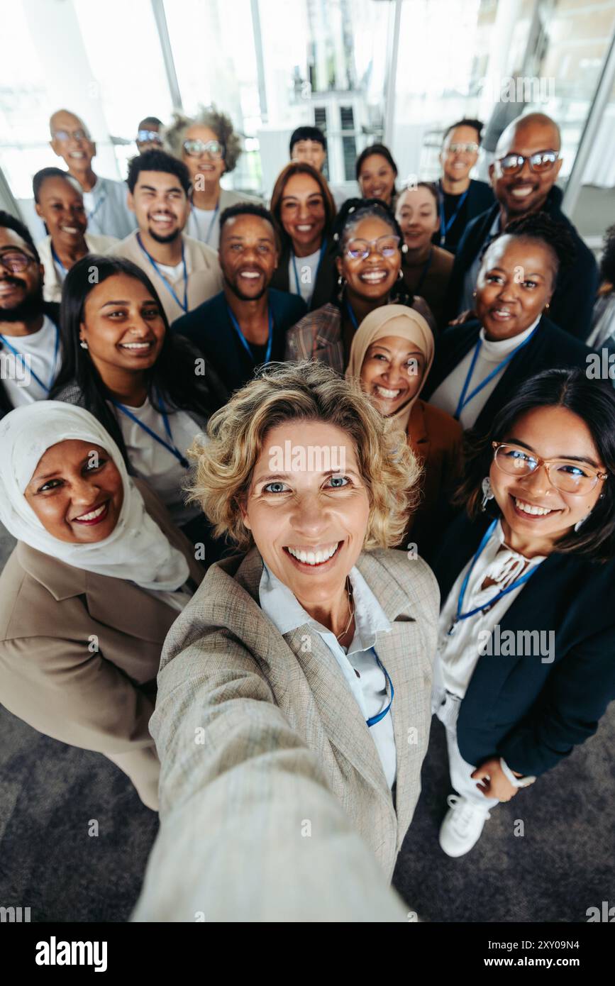 A diverse group of company staff smiling and taking a selfie at the ...