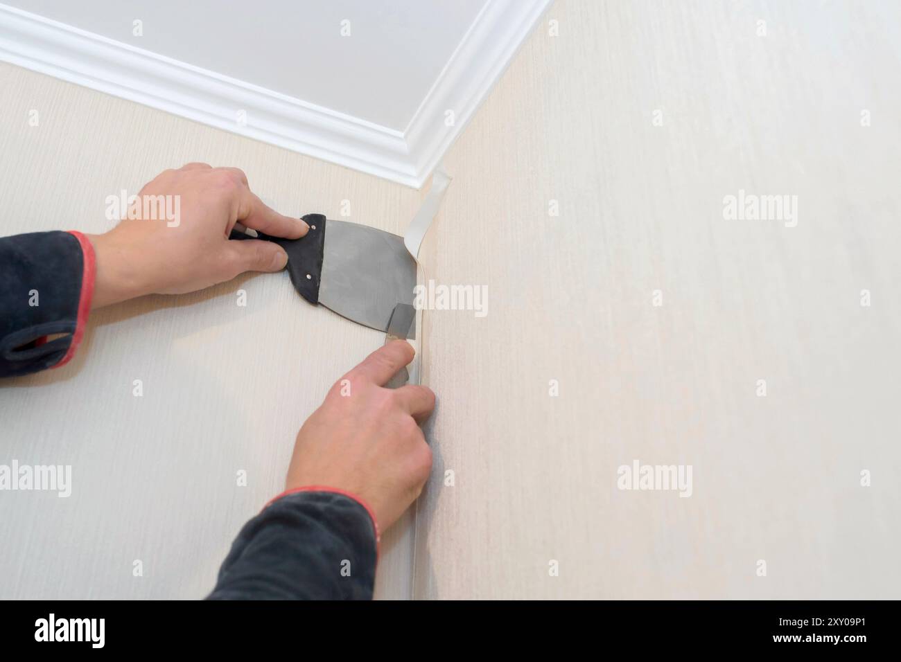 A man cuts the wallpaper with a clerical knife and a spatula. Apartment ...