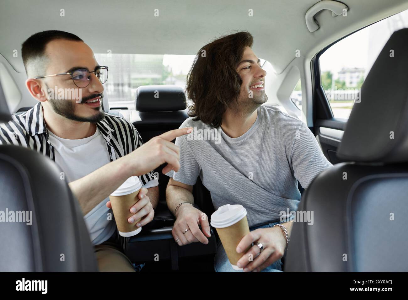 Two men in the backseat of a car, one pointing and laughing, both ...