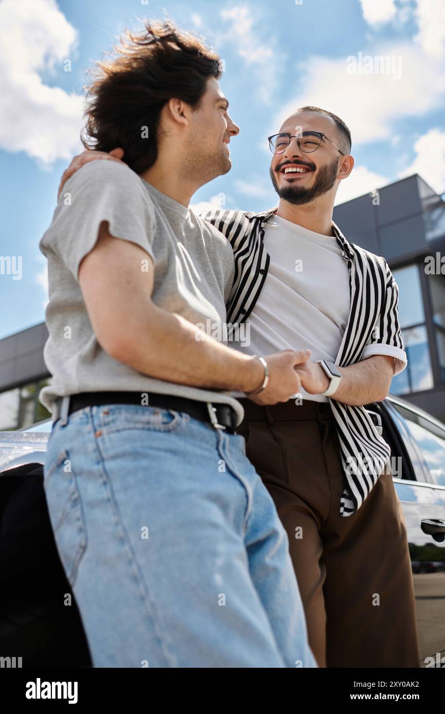 Two men in love, standing beside a car, laughing and sharing a tender ...