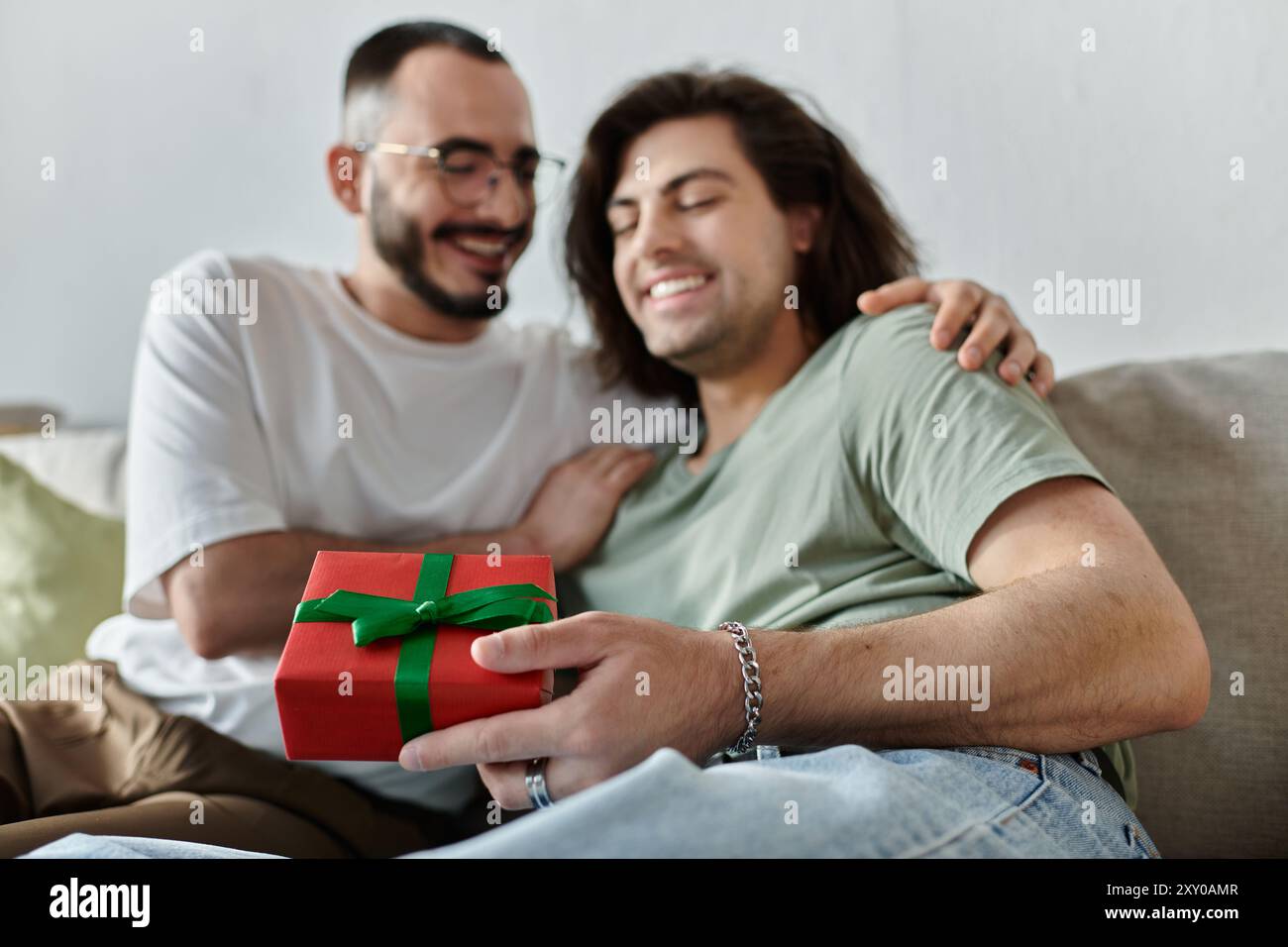 A gay couple laughs and smiles as one gives the other a gift Stock ...