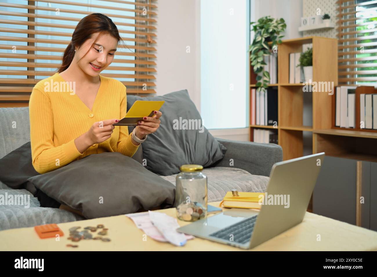 Young woman budgeting or reviewing her savings in living room. Personal ...