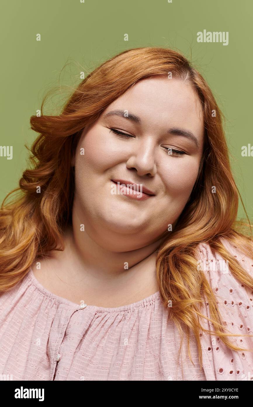 A beautiful, plus-size woman in an elegant pink blouse smiles softly ...