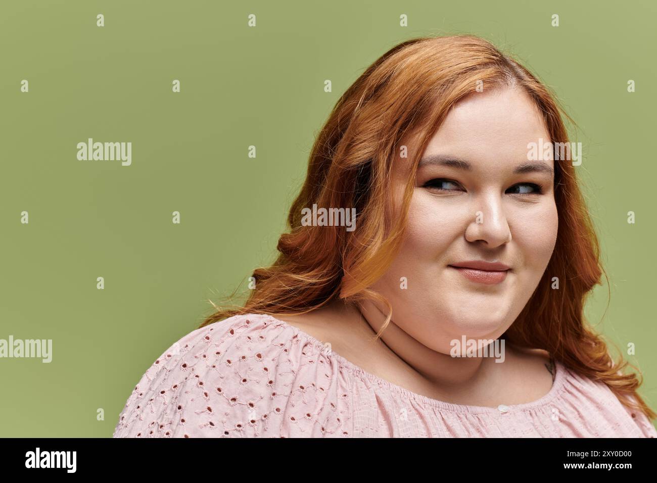 A plus-size woman with red hair smiles confidently at the camera Stock ...