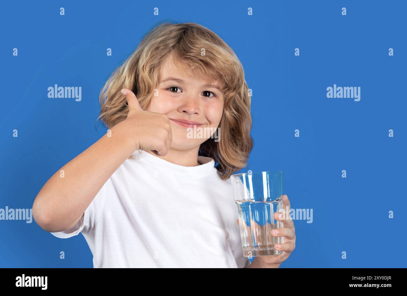 Little kid drinking a fresh glass of water, isolated on studio ...