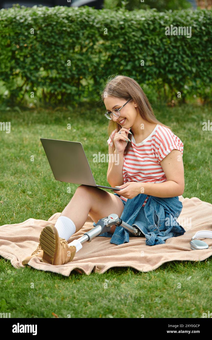 A young woman with a prosthetic leg works on her laptop while sitting ...
