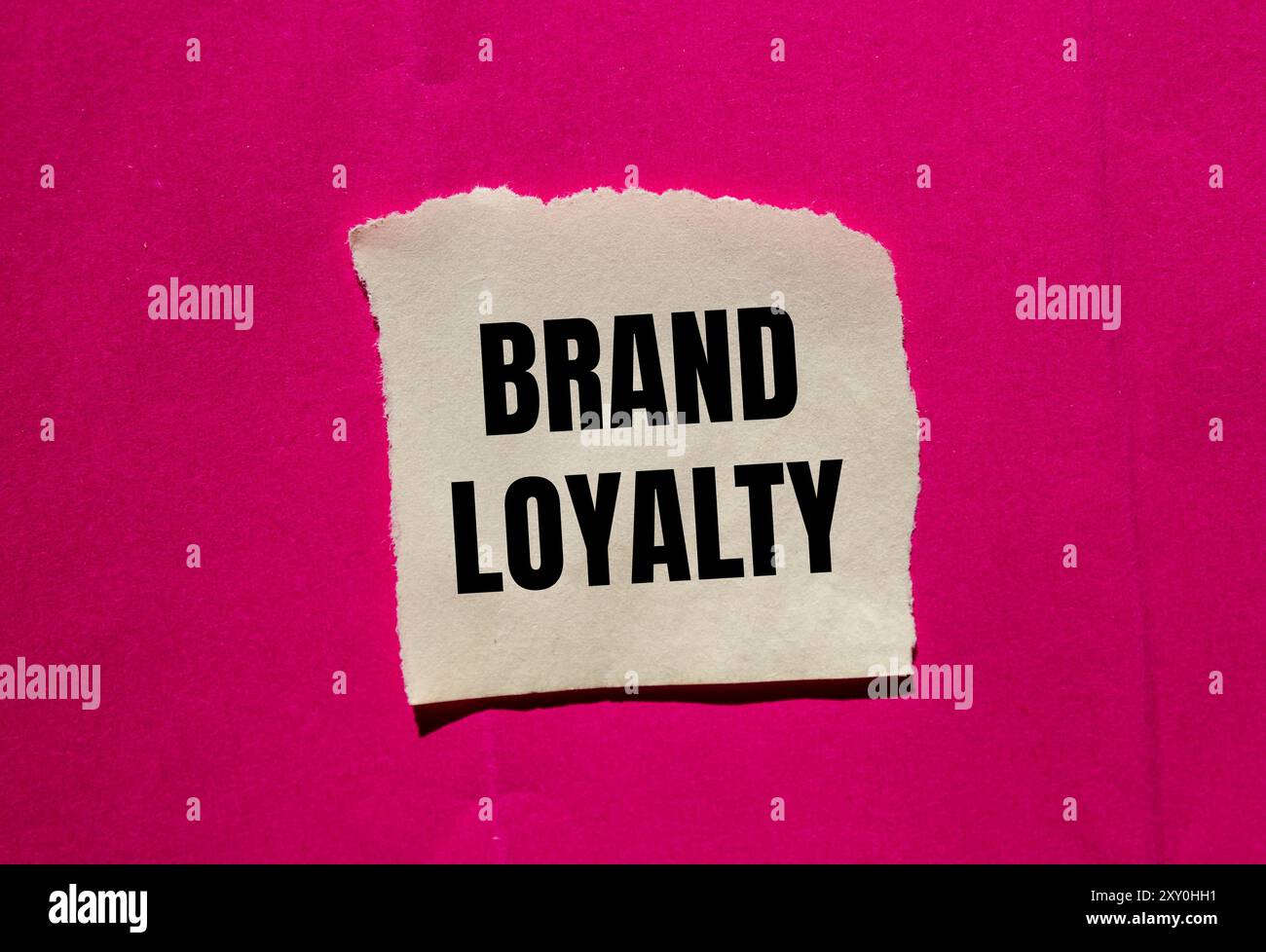 Brand loyalty message written on ripped torn paper piece on pink ...