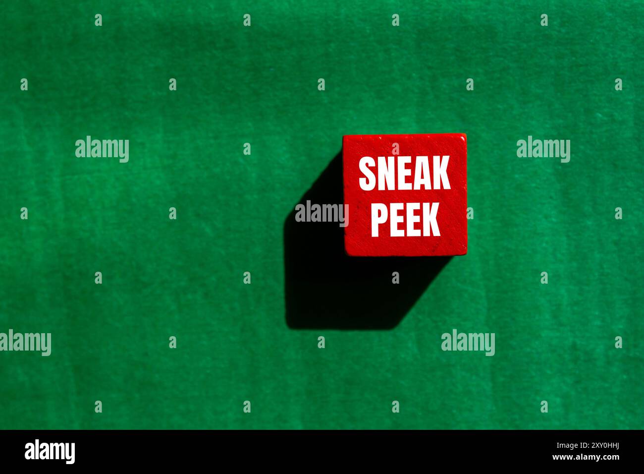 Sneak peek message written on red wooden cube with green background ...