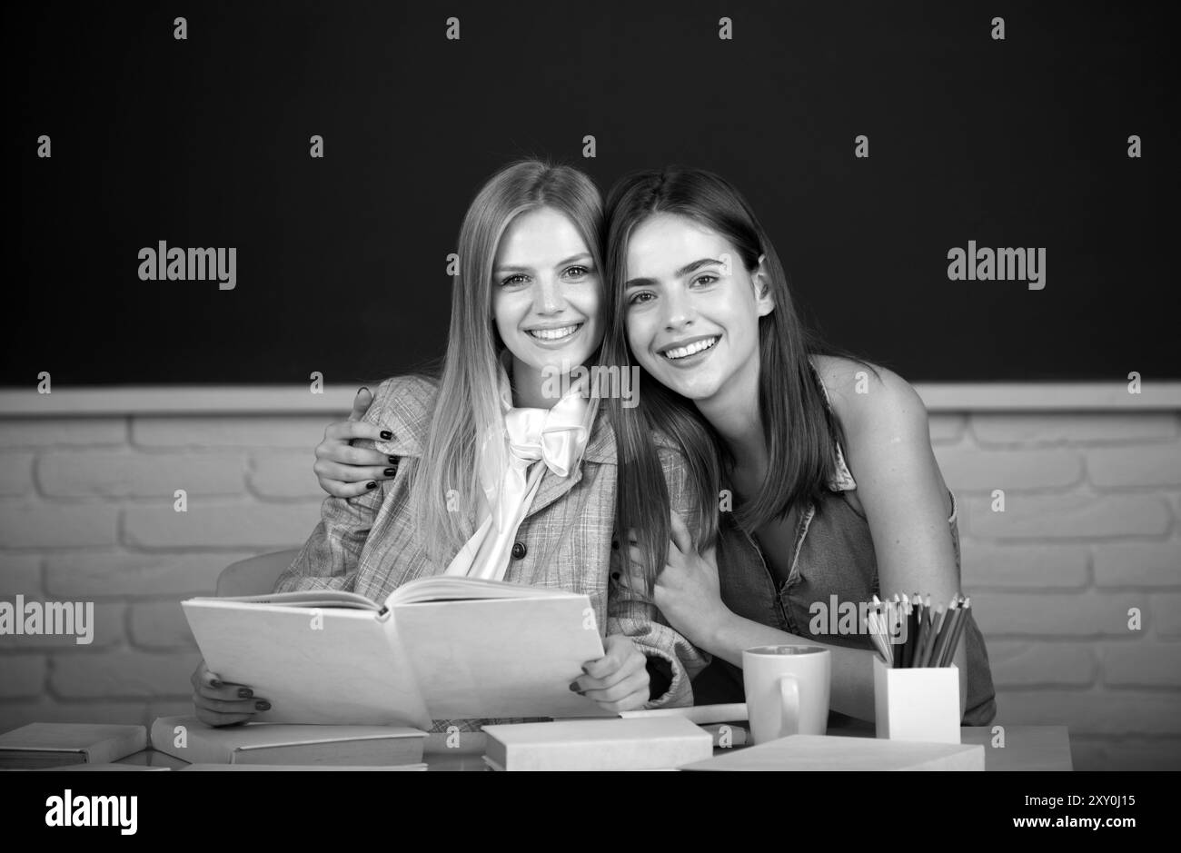Beautiful students girls hugging and embrace in classroom at school ...