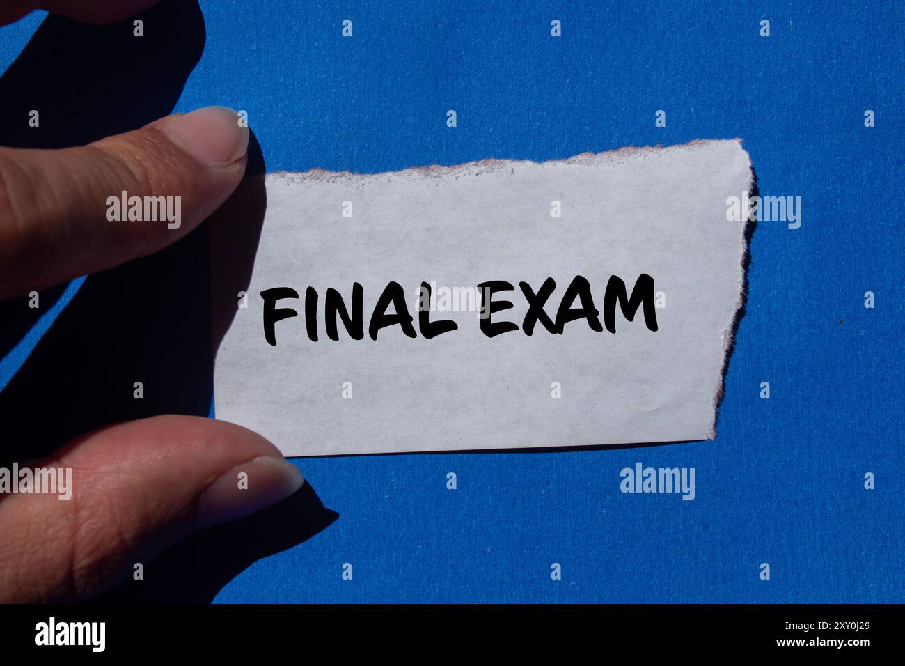 Final exam message written on ripped torn paper with blue background ...