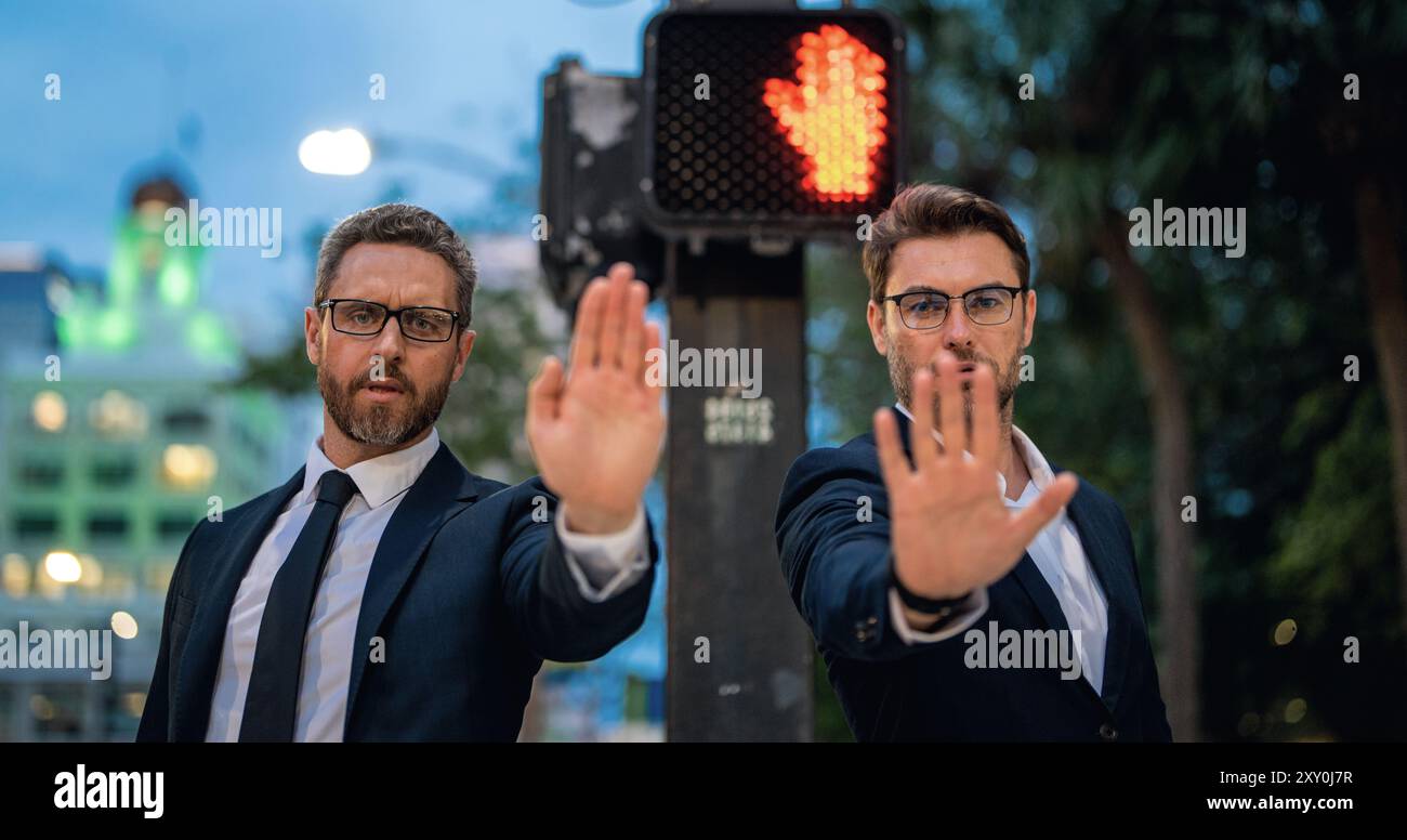 Two handsome business men in suit doing stop sing with hand. Warning ...