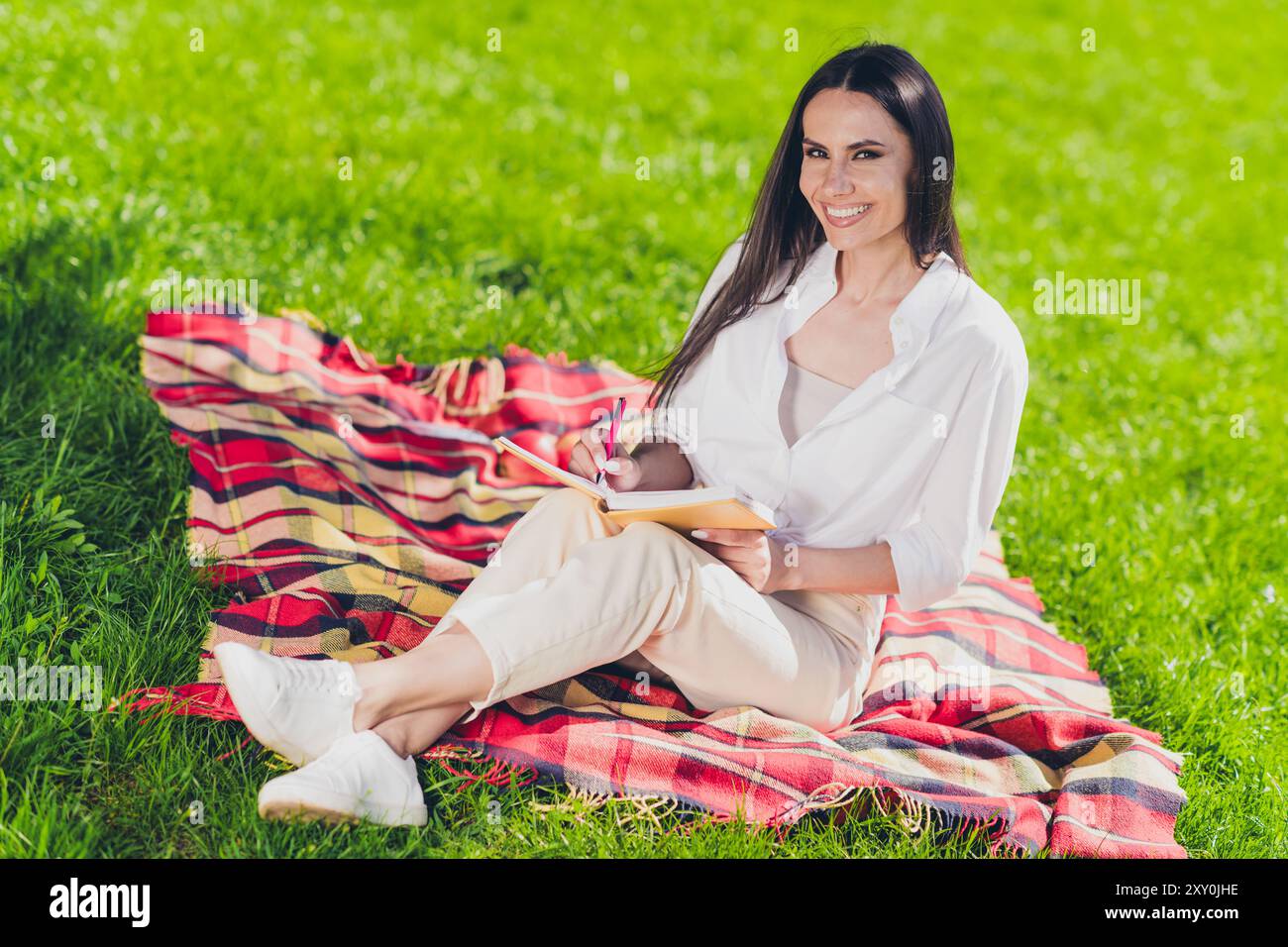 Full body photo of young cheerful woman sit picnic blanket write diary ...
