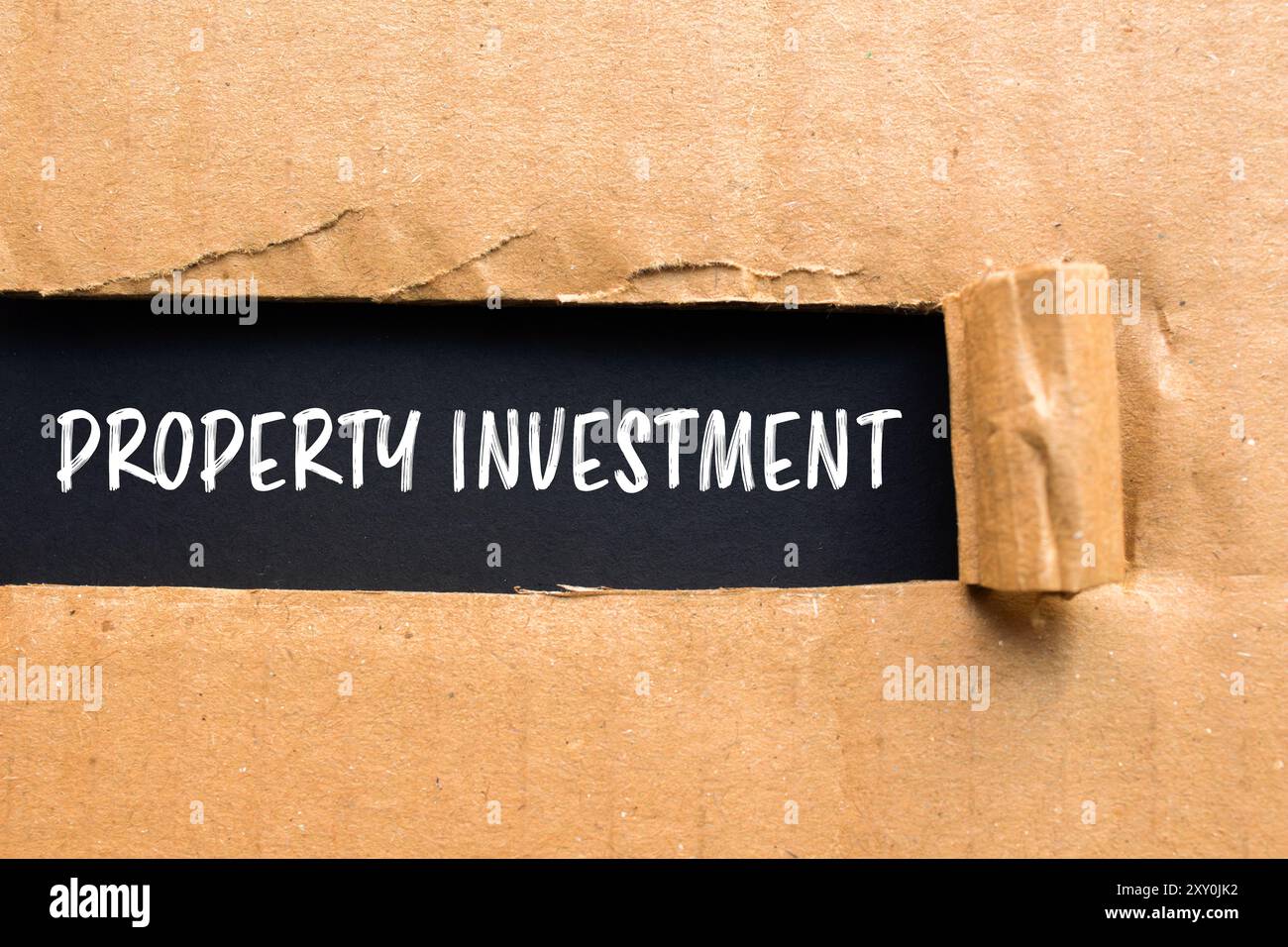 Property investment message written on ripped torn cardboard paper with black background ...