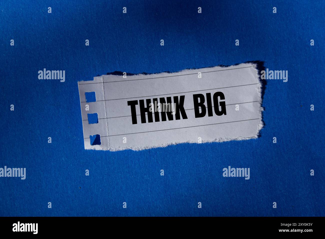 Think big message written on ripped torn paper piece with blue ...