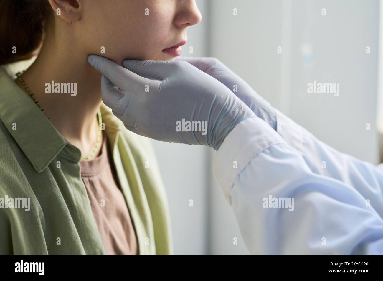Healthcare professional examining patient's neck with medical gloves ...