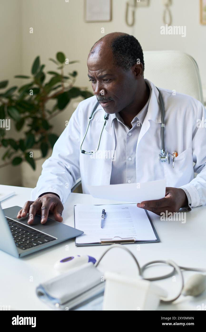 Senior doctor working in medical office, viewing patient records on ...