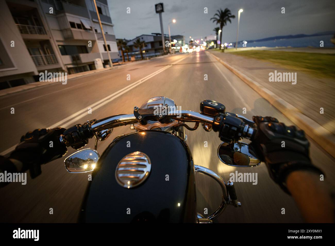 A wide-angle shot from behind a motorcyclist riding a chopper-style ...