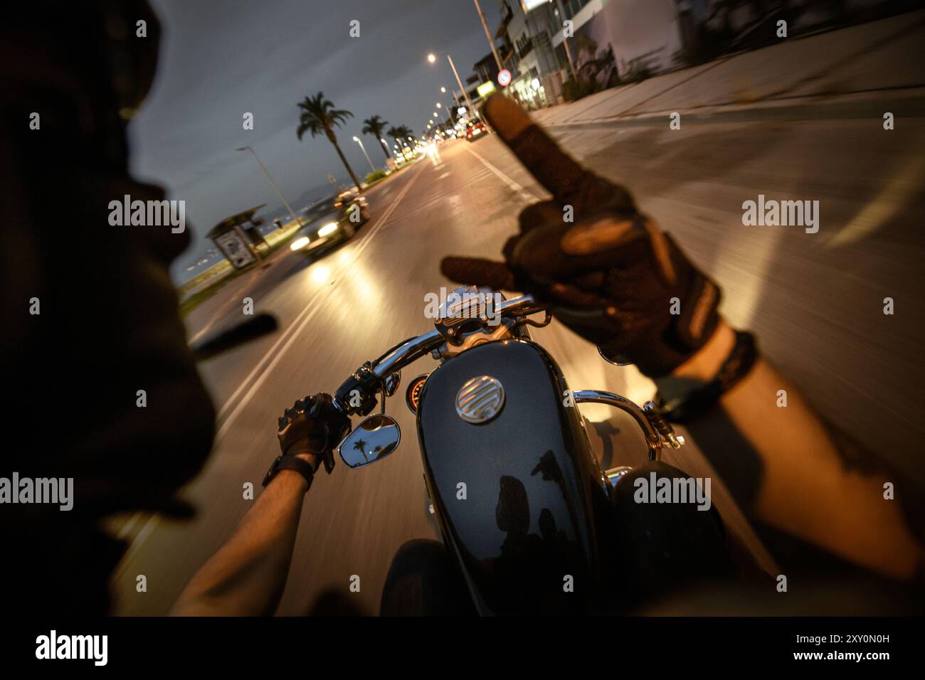A wide-angle shot from behind a motorcyclist riding a chopper-style ...