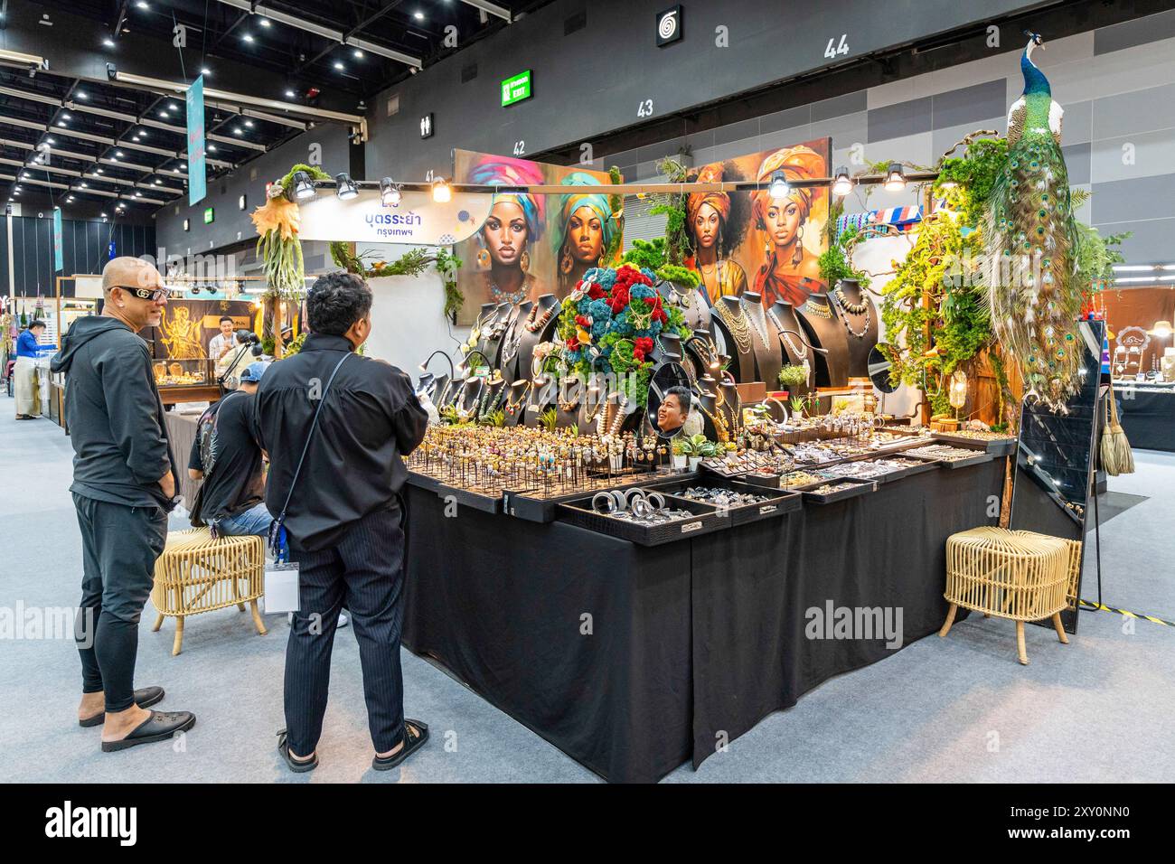 An exhibitor and a visitor are seen talking in front of a booth with ...