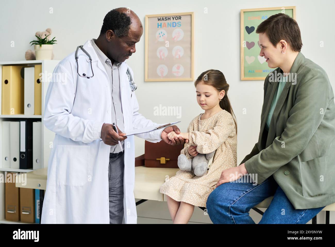 Pediatrician consulting with child and mother during medical exam ...