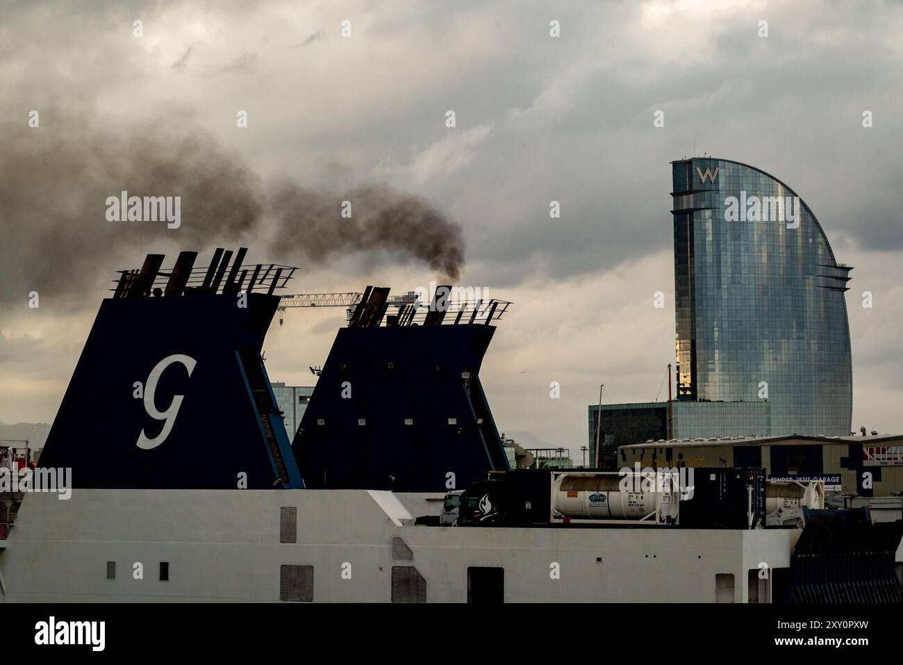 In the port of Barcelona a ferry ship’s funnels give off smoke as it ...