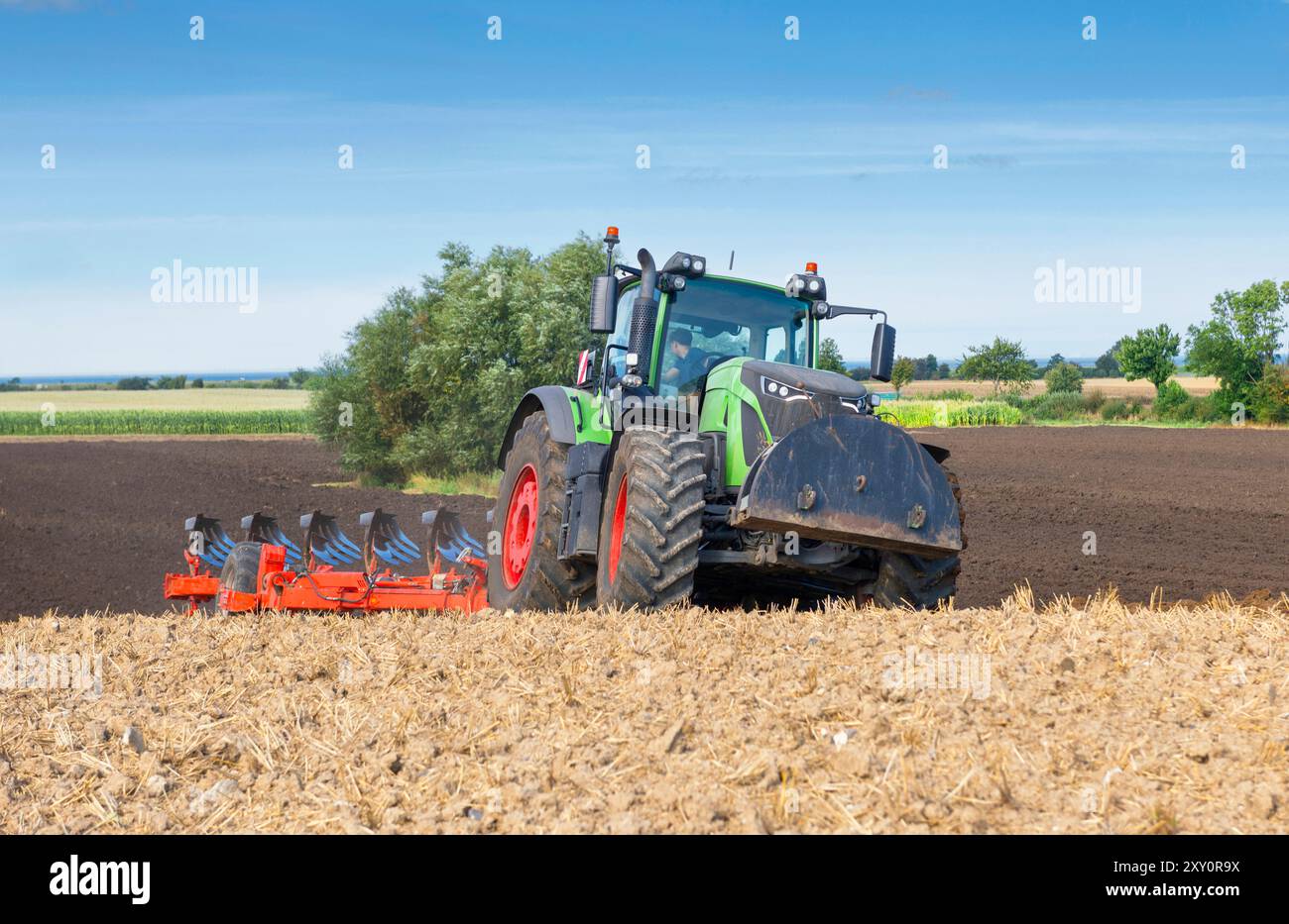 Tractor with 7-blade reversible plough and packer in the field, after ...
