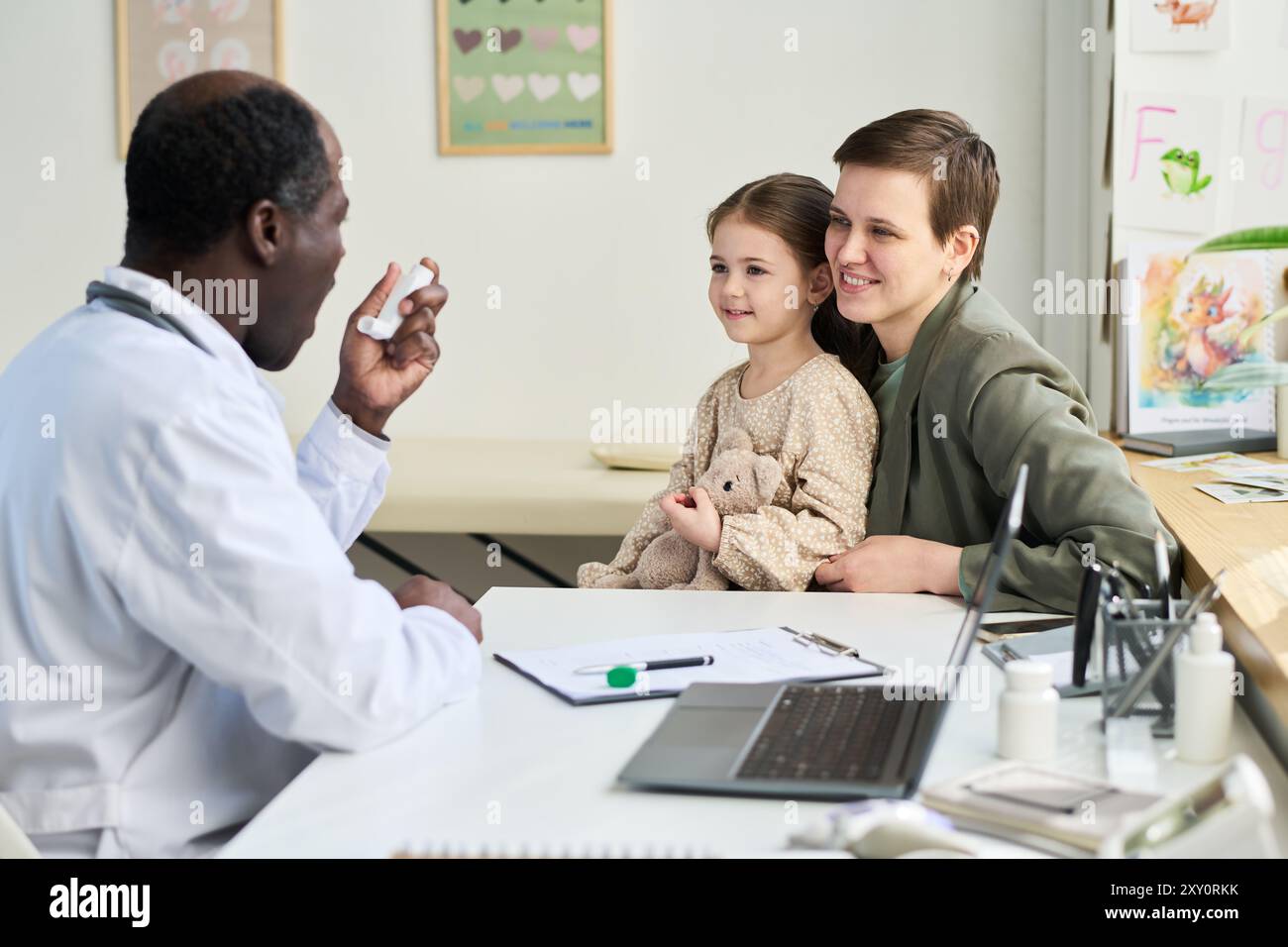 Doctor explaining medication to smiling mother and daughter in office ...