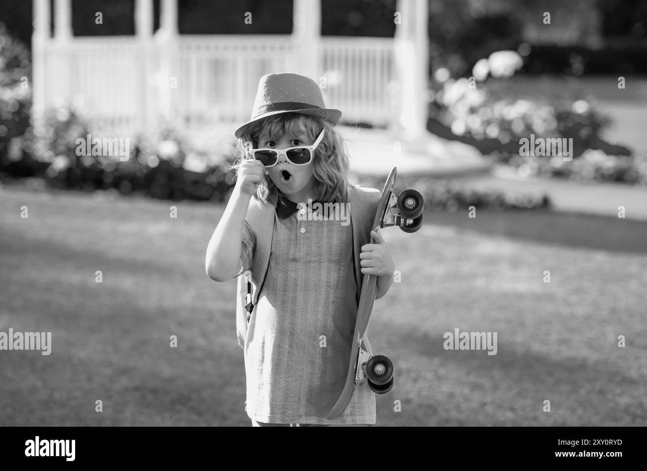 Childhood and fashion. Cute child with skateboard on summer park ...