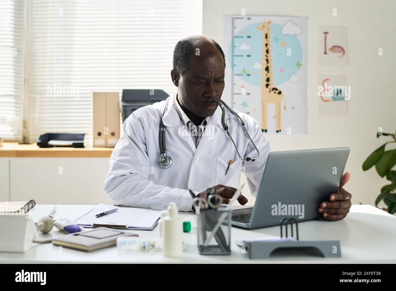 African American doctor reviewing patient medical records on laptop in ...