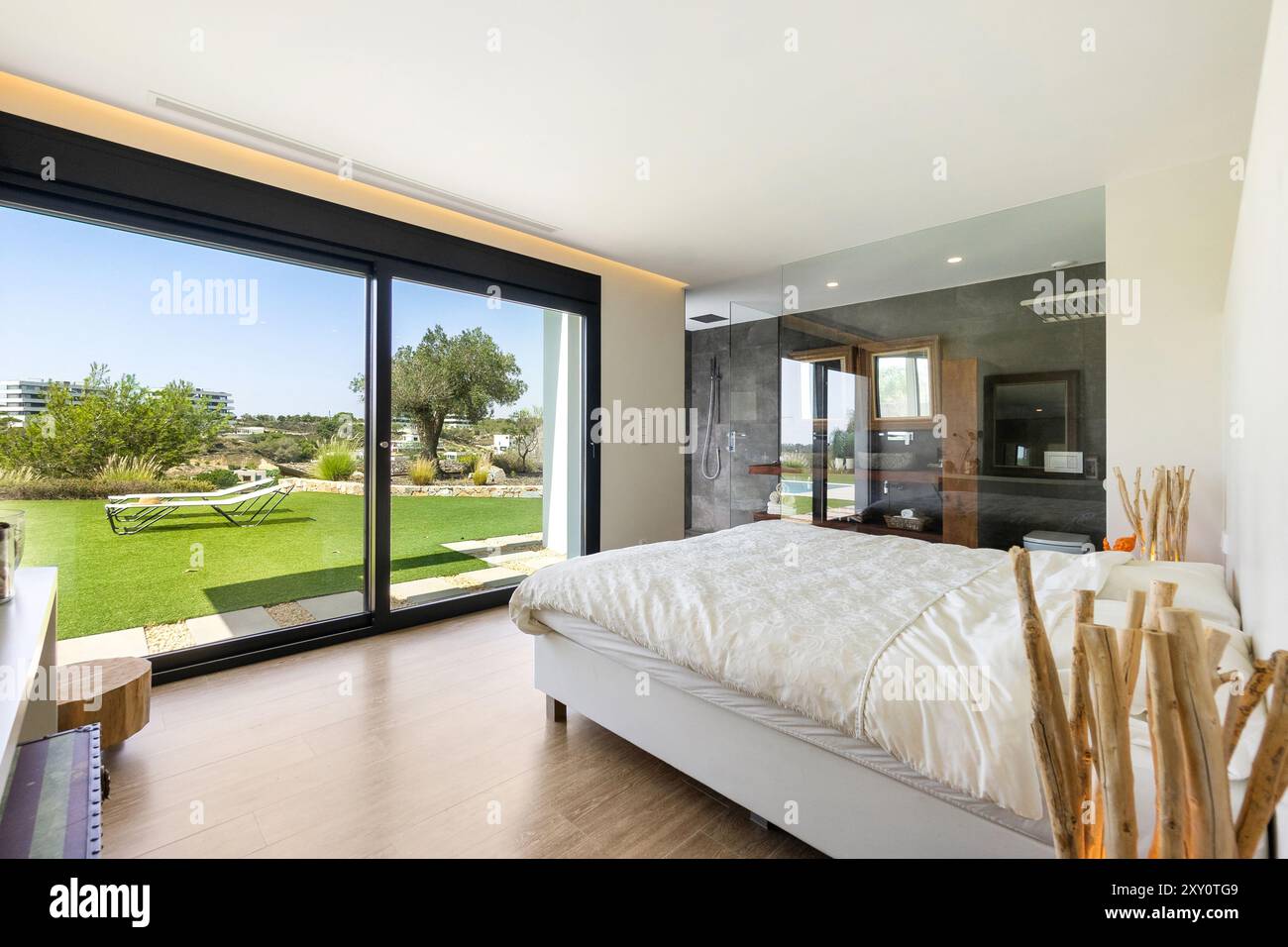 A modern, spacious bedroom featuring a large sliding glass window with ...