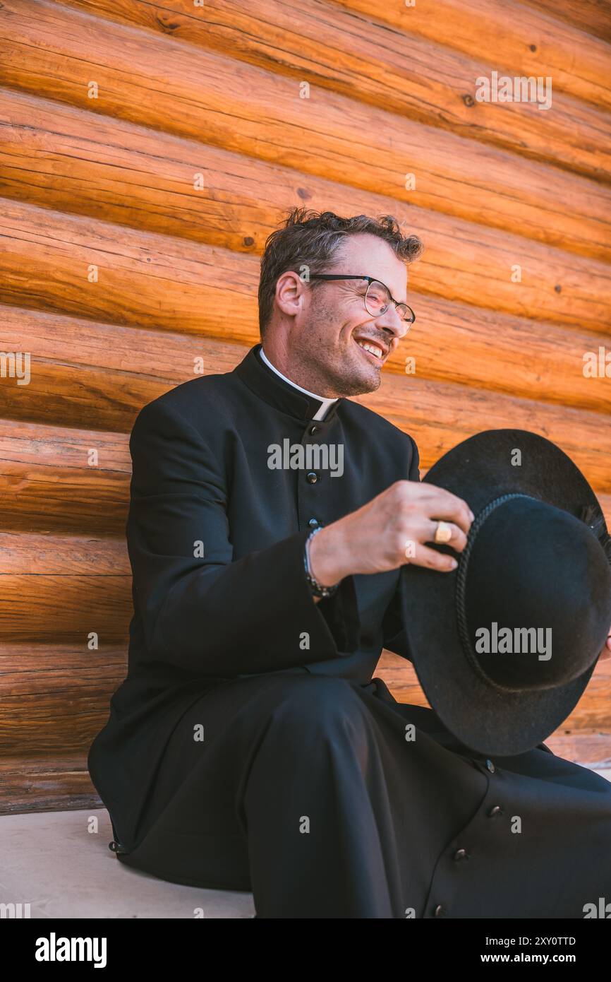 A Catholic priest in traditional attire laughs joyfully while holding ...