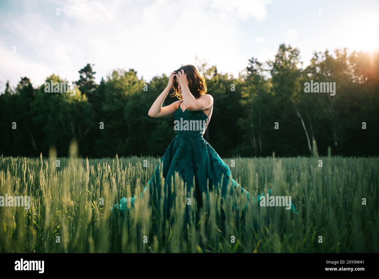 A young woman in an exquisite green prom dress stands amidst a vibrant ...