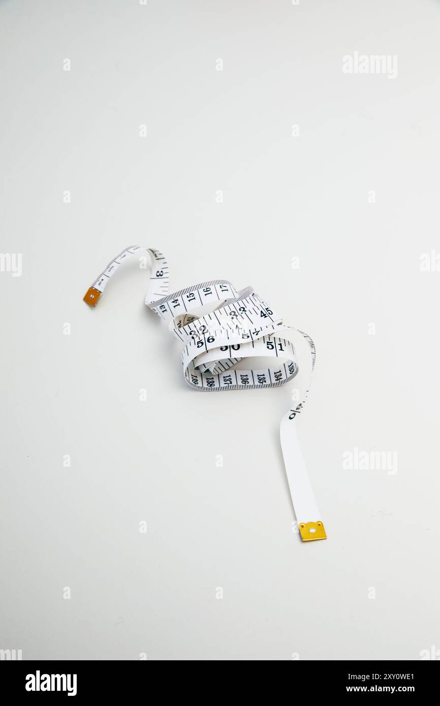 Top view of a simple white measuring tape coiled against a clean white ...