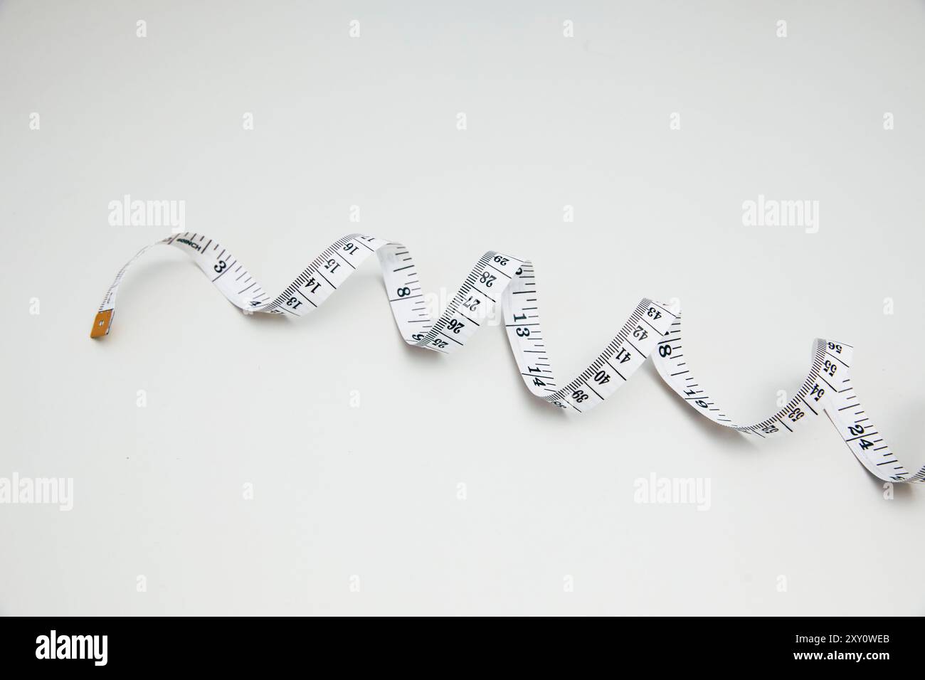 Top view of a simple white measuring tape loosely curled on a clean ...