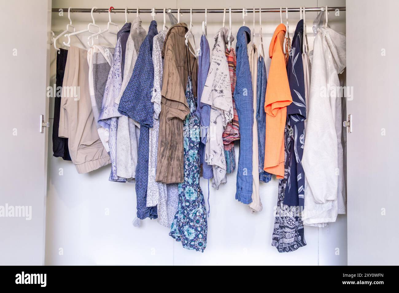 A variety of clothes hanging in a wardrobe, demonstrating a ...