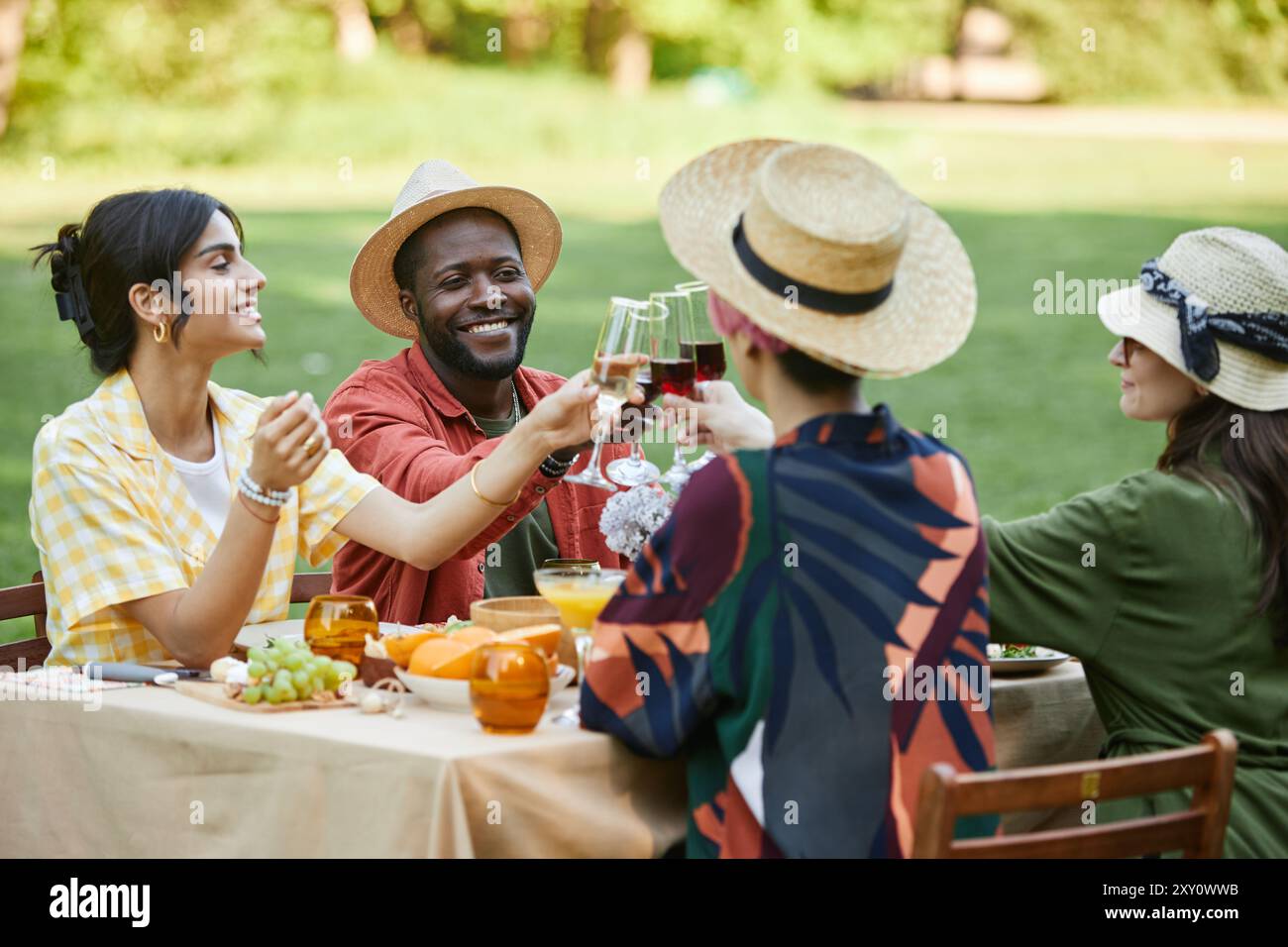 Group of friends enjoying picnic outdoors, sharing food and drinks in ...